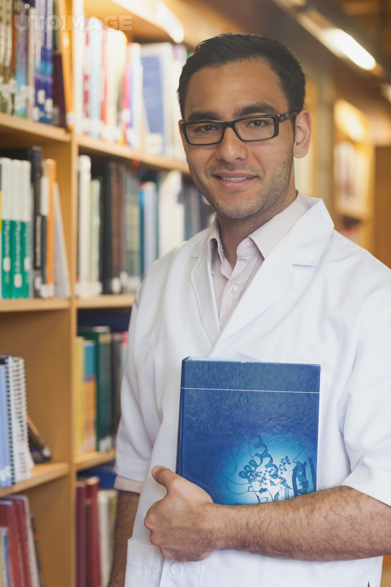 유토이미지 | Attractive intellectual man posing in library holding a book