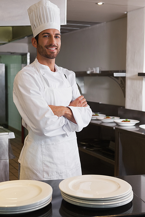 유토이미지 | Happy head chef standing with arms crossed behind counter