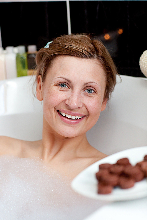 유토이미지 | Radiant woman eating chocolate while having a bath