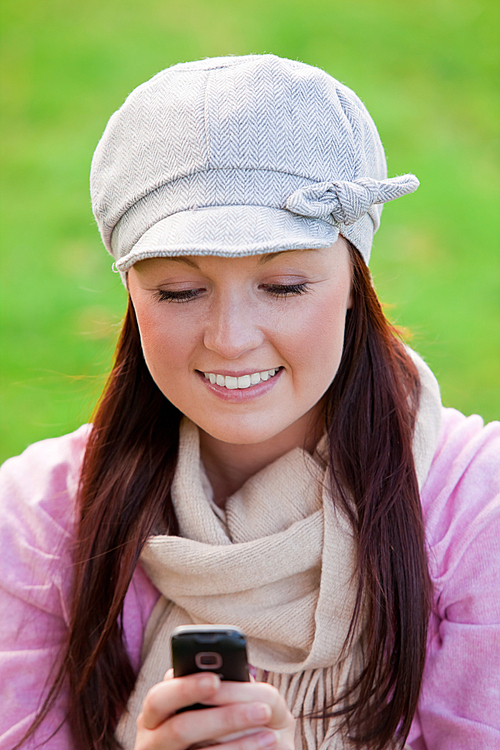 Pretty young woman wearing cap and scarf sending a message with her ...