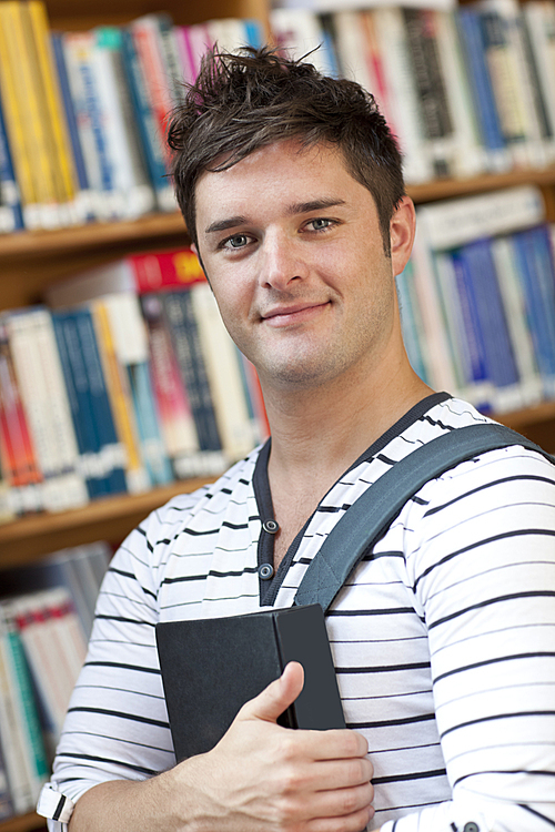 Portrait of a smart student holding a book standing in the library | 유토 ...