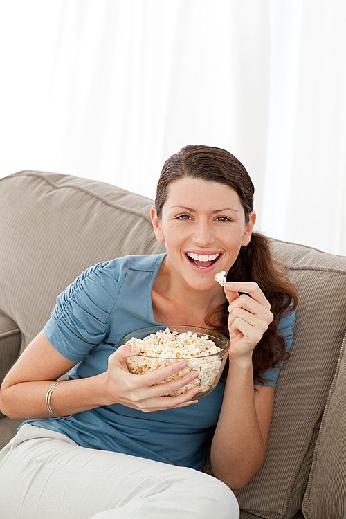 유토이미지 | Portrait of a happy woman eating pop corn while watching television