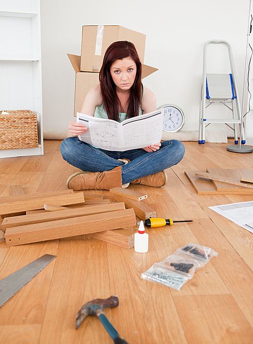 Good looking redhaired female reading a manual before do-it-yourself ...