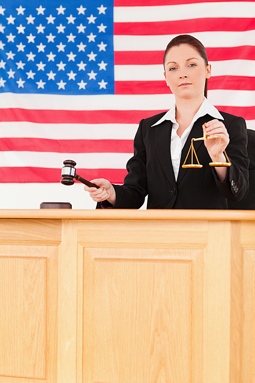 유토이미지 | Young judge knocking a gavel and holding scales of justice