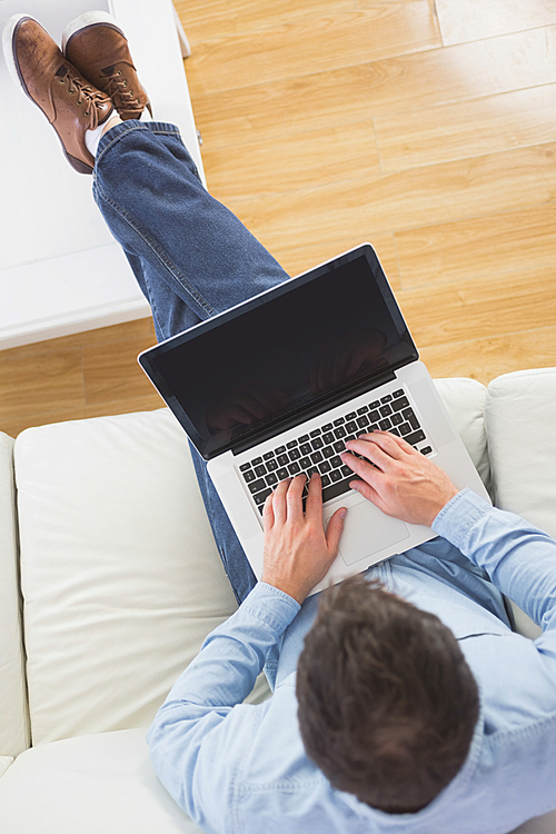 High angle view of casual man typing on laptop with feet on table | 유토 ...