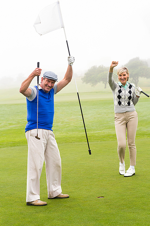 유토이미지 | Golfing couple cheering on the putting green on a foggy day at ...