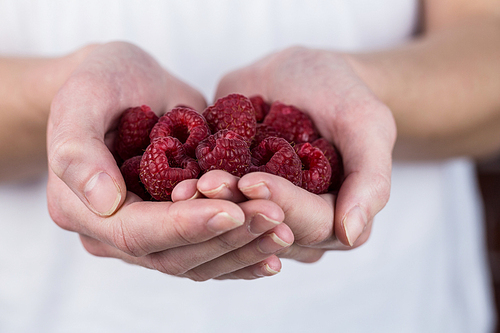 유토이미지 | Woman showing handful of raspberries in close up