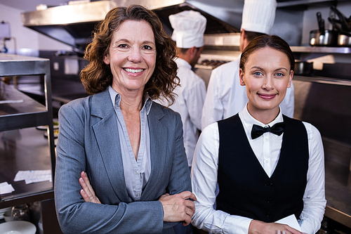 Portrait of female restaurant manager and waitress smiling in ...