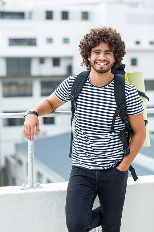 Portrait of happy young man wearing rucksack standing on terrace | 유토 ...