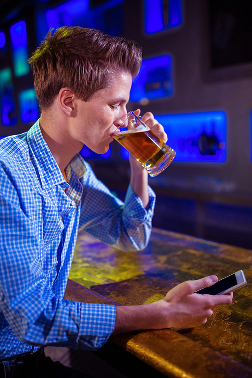 유토이미지 | Young man with mobile phone drinking beer at bar counter