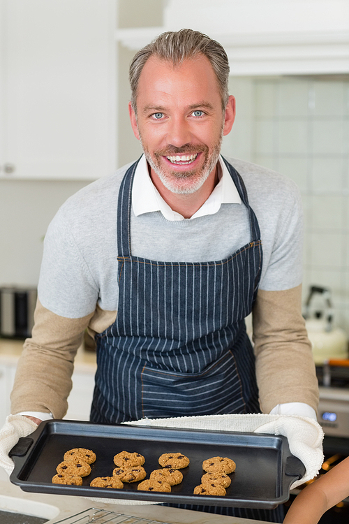 유토이미지 | Portrait of smiling man holding a cookies in baking tray at kitchen