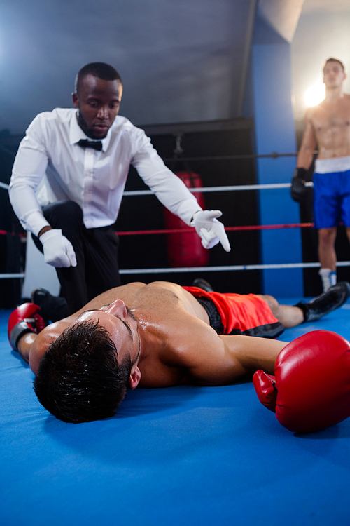 유토이미지 | Male boxer looking while referee counting by athlete in boxing ring