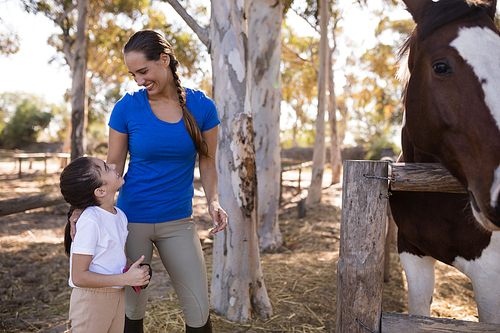 유토이미지 | Smiling woman looking at girl while standing by horse