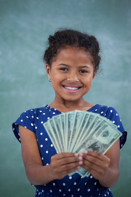 Close up portrait of smiling girl showing paper currency against wall ...