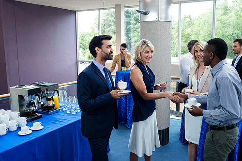 Business executives interacting with each other while having coffee at ...
