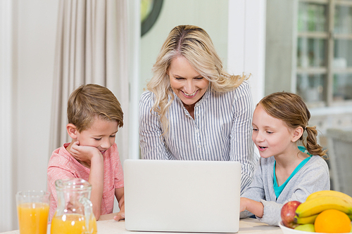 유토이미지 | Mother and his kids using laptop while having breakfast in kitchen