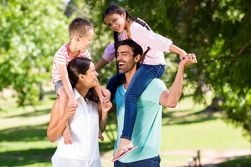 유토이미지 | Portrait of parents carrying their children on shoulder in park ...