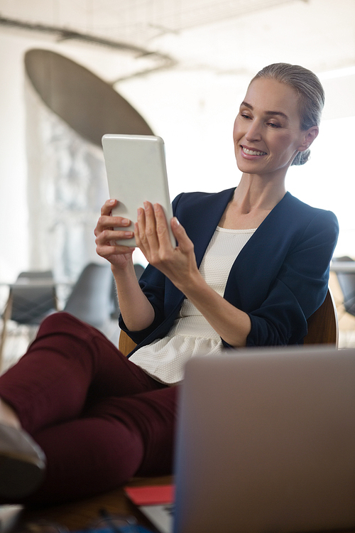 유토이미지 | Businesswoman using tablet computer while sitting on chair at ...