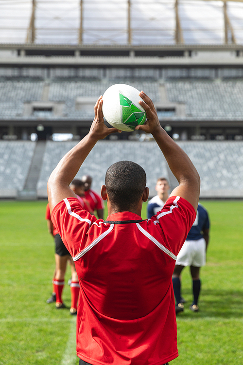 Rear view of handsome African American male rugby player throwing rugby ...