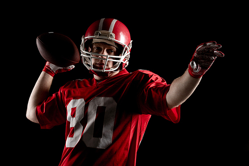 유토이미지 | American football player throwing rugby ball against black ...