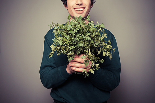 유토이미지 | A happy young man is holding a big bunch of fresh parsley