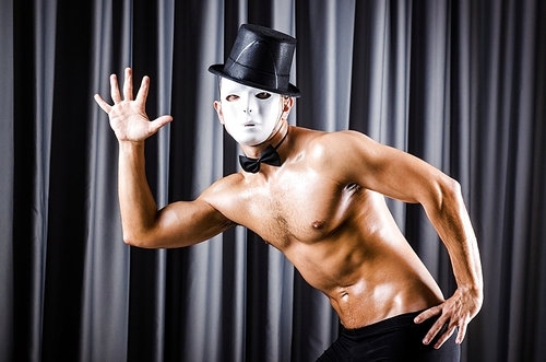 유토이미지 | Muscular actor with mask against curtain