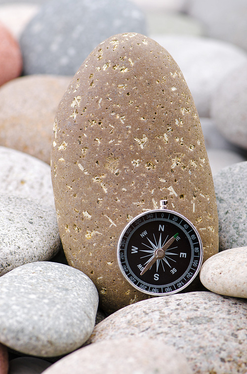 유토이미지 | Navigation compass on stone pebbles
