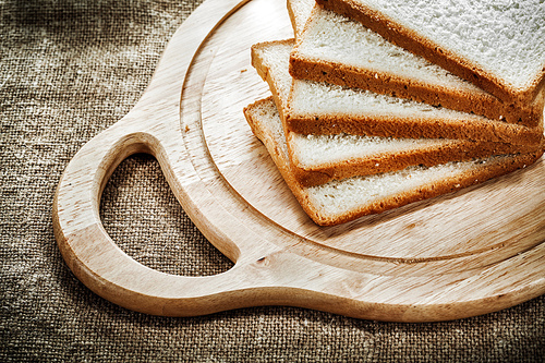 유토이미지 | Chopping board sliced toast bread on textured sacking background.