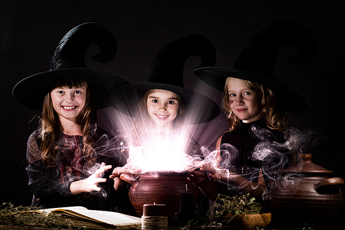 유토이미지 | Three little Halloween witches reading spell above pot