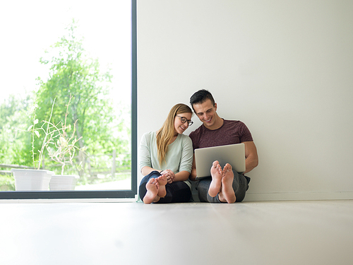 Young couple using laptop computer on the floor at luxury home together ...
