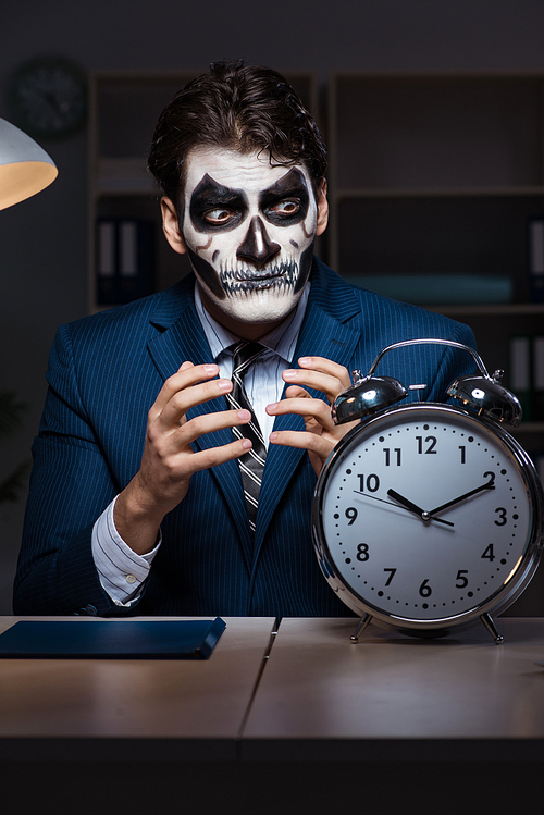 유토이미지 | Businessman with scary face mask working late in office