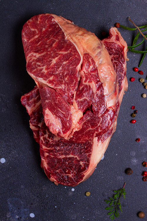 유토이미지 | Raw beef steak with spices on dark stone background, top view