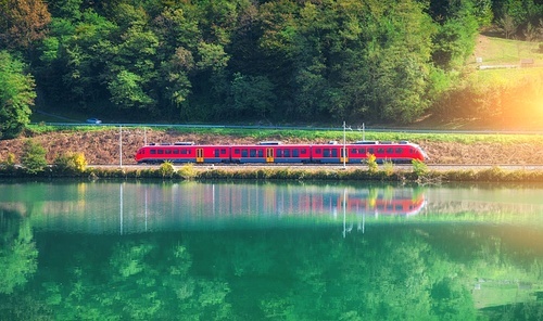 Beautiful red modern high speed train and river in alpine mountains at ...