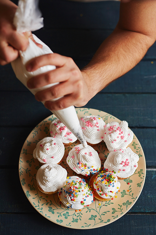 유토이미지 | Close-up of a human hand frosting a cake with whipped cream