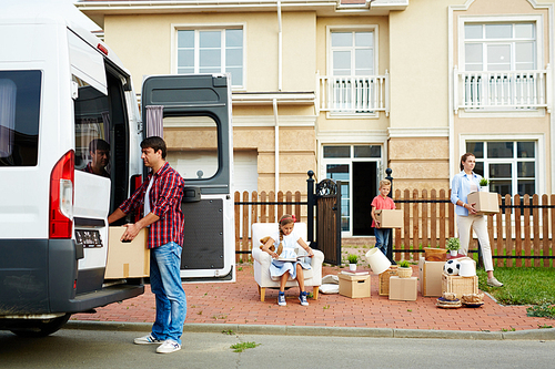 Family with two kids bringing cardboard boxes out from the house to ...