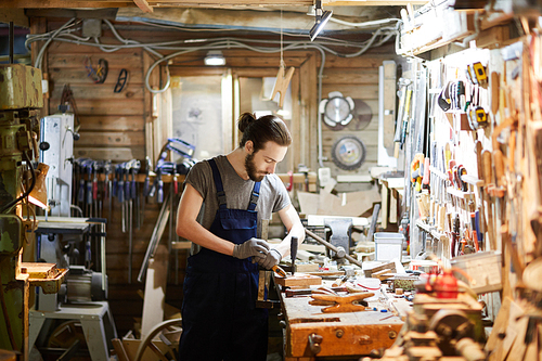 유토이미지 | Young man in overalls standing by workbench and processing ...