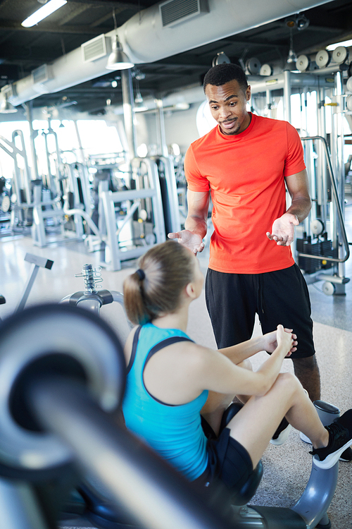 Young professional trainer talking to sportswoman in gym after workout ...