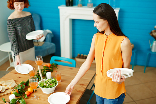 유토이미지 | Two attractive females putting white plates onto wooden table ...