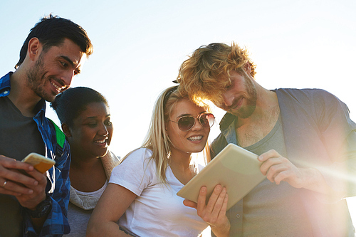 유토이미지 | Group of modern teenagers using gadgets while gathering outdoors