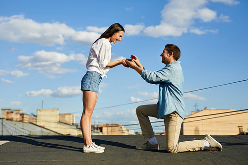 Happy loving man getting on one knee and opening jewelry box with ...