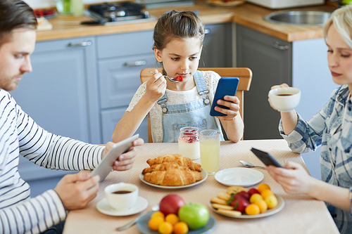 유토이미지 | Modern family using mobile gadgets while having breakfast by ...