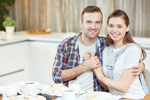 Cheerful and amorous young couple with smiles while sitting by served ...