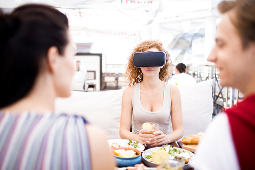 유토이미지 | Young woman in vr goggles sitting by served table in front of ...