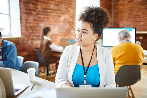 유토이미지 | Young mixed-race banker in smart casual sitting by desk in ...