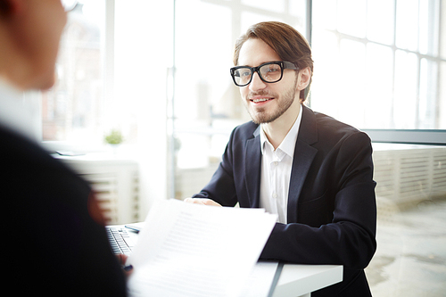 Bearded young manager wearing classical suit sitting opposite his ...