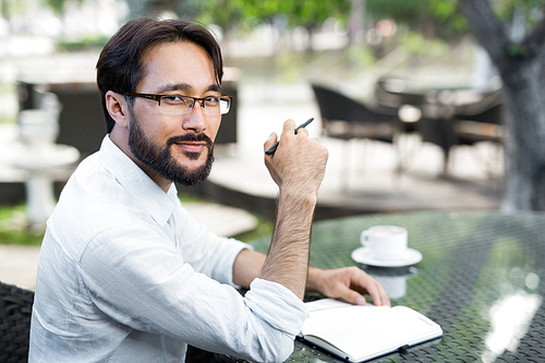 Middle-aged Asian interior designer with slight smile while sitting in ...
