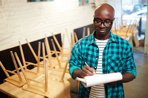 유토이미지 | Young worker of cafe with notepad making revision of all supplies