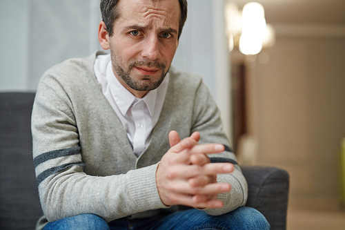 Portrait of middle-aged man in despair while sitting in private ...