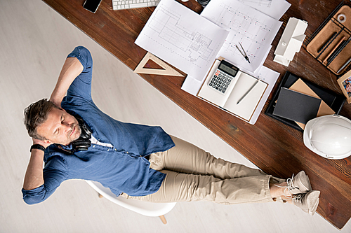 Top view of relaxed engineer in casualwear sitting on chair with his ...