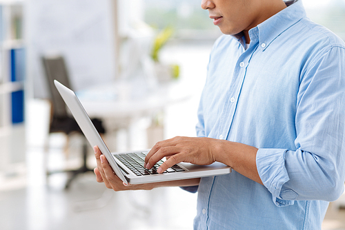 Profile view of unrecognizable young manager wearing blue shirt working ...